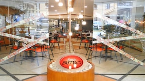 Um restaurante com uma mesa central de exposição, diversas áreas de estar e chão de azulejos.