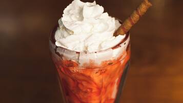 Sobremesa em copo alto com chantilly e um pirulito.