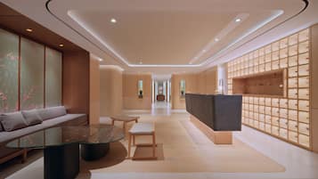 Um lobby moderno de hotel, com balcão de recepção, área de estar e uma parede decorativa.