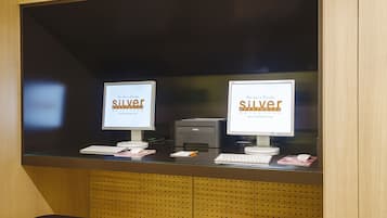 Dois monitores de computador exibindo o texto "Silver Hotel", colocados sobre uma mesa com teclado e impressora.