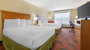 Quarto de hotel com duas camas, uma mesa, uma televisão e uma janela.