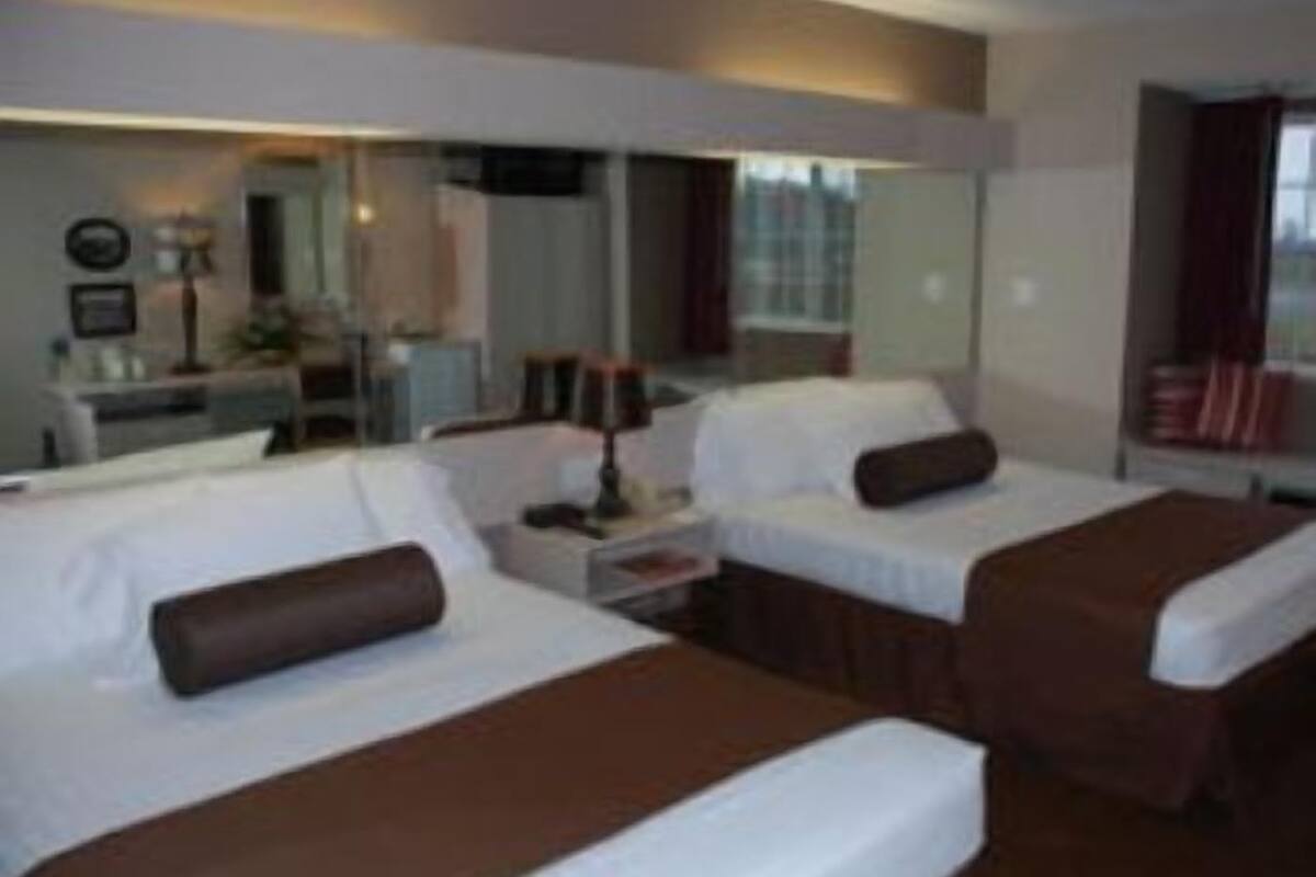 Quarto de hotel com duas camas, uma escrivaninha, uma cadeira e um espelho grande.