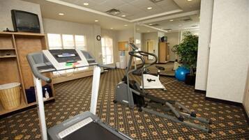 Sala de ginástica de hotel com esteira, elíptica e bicicleta ergométrica.