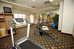 Sala de ginástica de hotel com esteira, elíptica e bicicleta ergométrica.