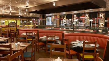 Um restaurante com cabines e mesas, cadeiras de madeira e um bar com garrafas e copos.