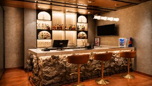Uma área de bar com balcão de pedra, banquetas, uma TV de tela plana e uma placa proibindo a condução.