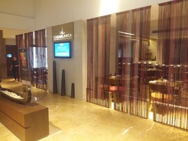 Um saguão de hotel com design moderno, exibindo uma placa com 'CASABLANCA' e uma tela mostrando 'NESTLE LTD. SENATE HALL'.