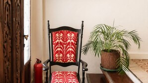 A room with a wooden chair, a framed picture, a potted plant, and a fire extinguisher.