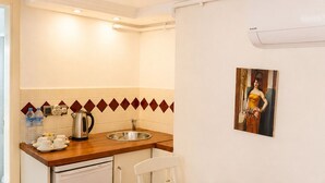 A compact kitchen with a refrigerator, sink, and a small dining table with chairs.