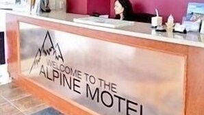 Uma mesa de recepção com uma placa que diz 'Welcome to the Alpine Motel'.