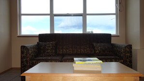 Uma sala de estar com sofá, mesa de centro e janela com vista para o céu.