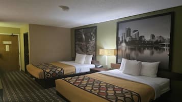 Quarto de hotel com duas camas, vista para a cidade, colcha estampada e uma luminária.