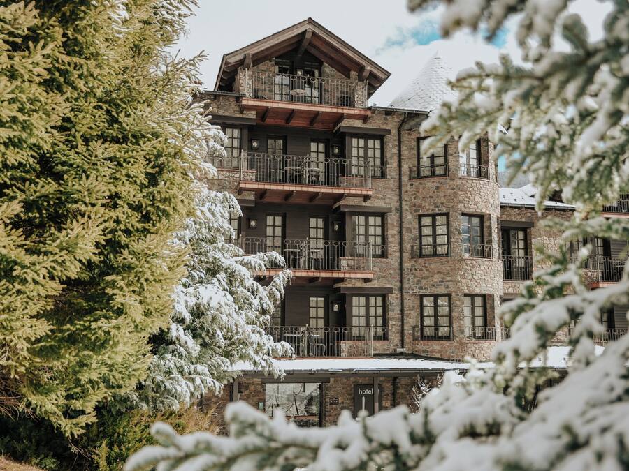 Um hotel de vários andares com fachada de pedra, varandas e paisagem nevada.