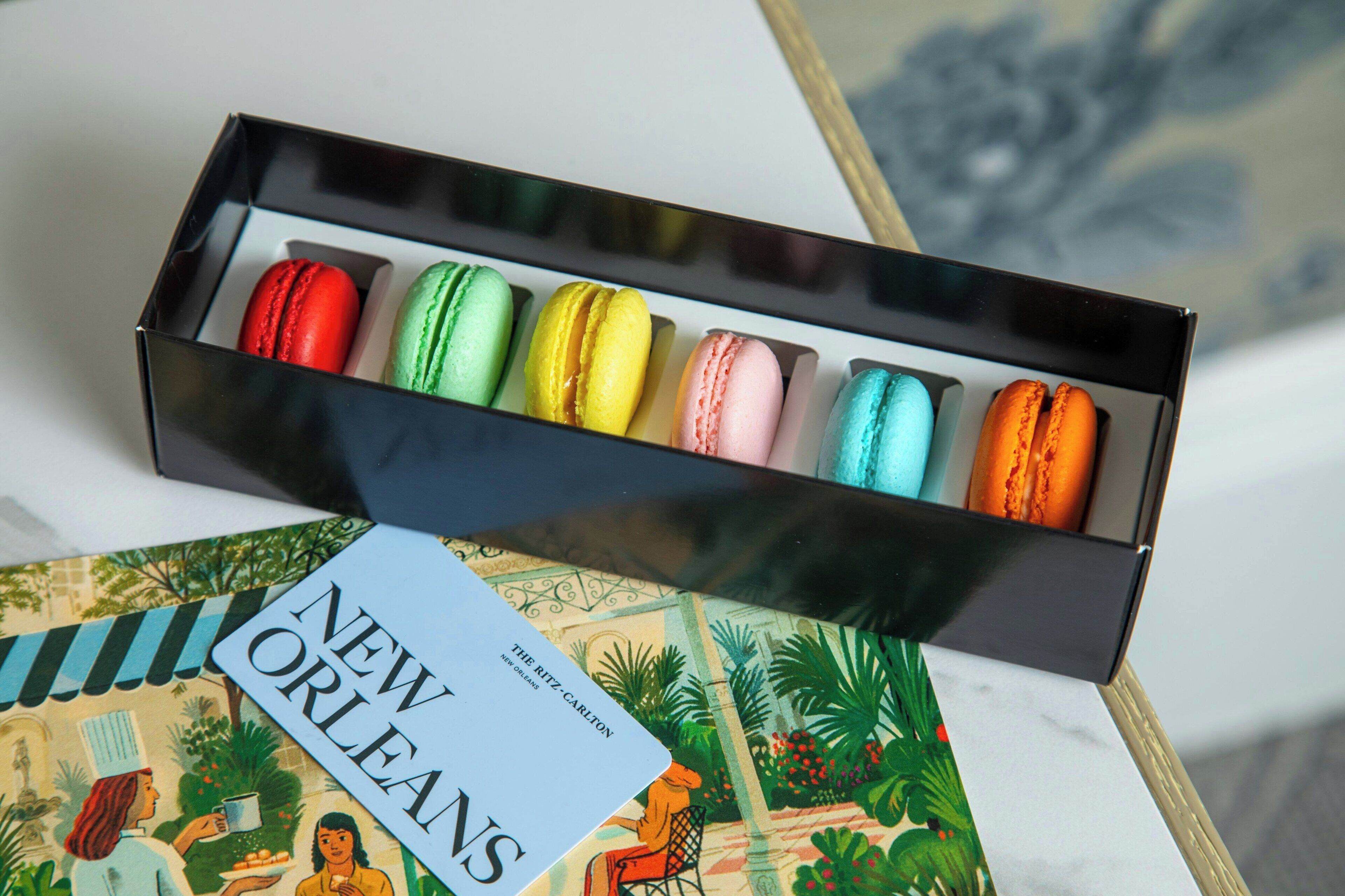 Caixa de macarons coloridos sobre uma mesa com um cartão que diz 'New Orleans'.