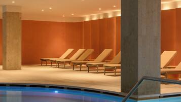 Área de piscina com espreguiçadeiras e um pilar de concreto.
