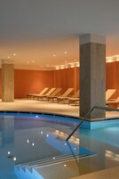 Área de piscina com espreguiçadeiras e um pilar de concreto.