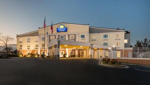 Edifício Days Inn & Suites com entrada coberta, várias janelas e uma bandeira americana.