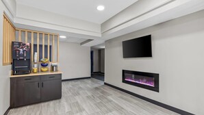 Um hall de hotel moderno com área de cozinha, televisão de tela plana e lareira.