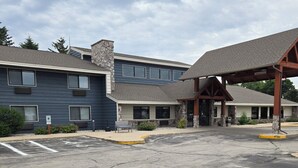 Um edifício com fachada de pedra, várias janelas e uma área de entrada coberta.