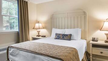 Quarto de hotel com cama, duas mesas de cabeceira, janela com cortinas e radiador.