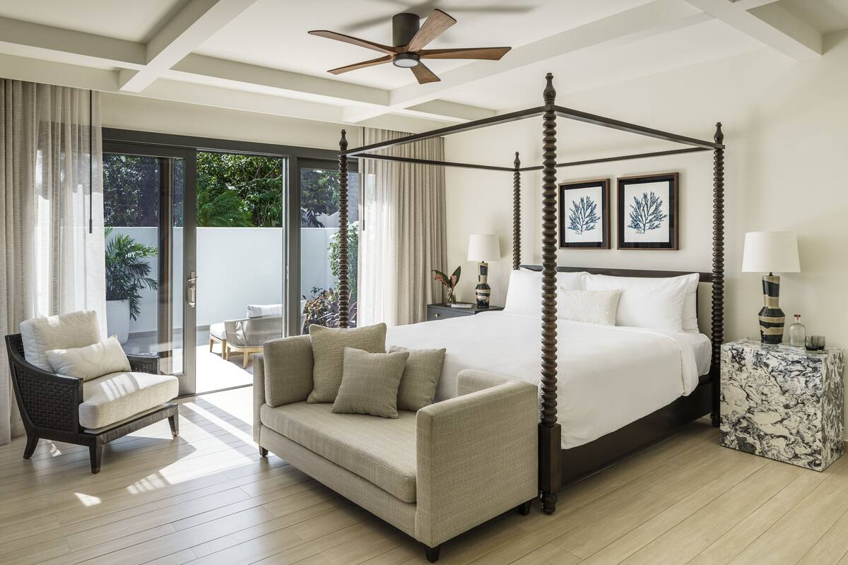 Um quarto espaçoso com cama de dossel, um sofá, uma mesinha de cabeceira e vista para o exterior.