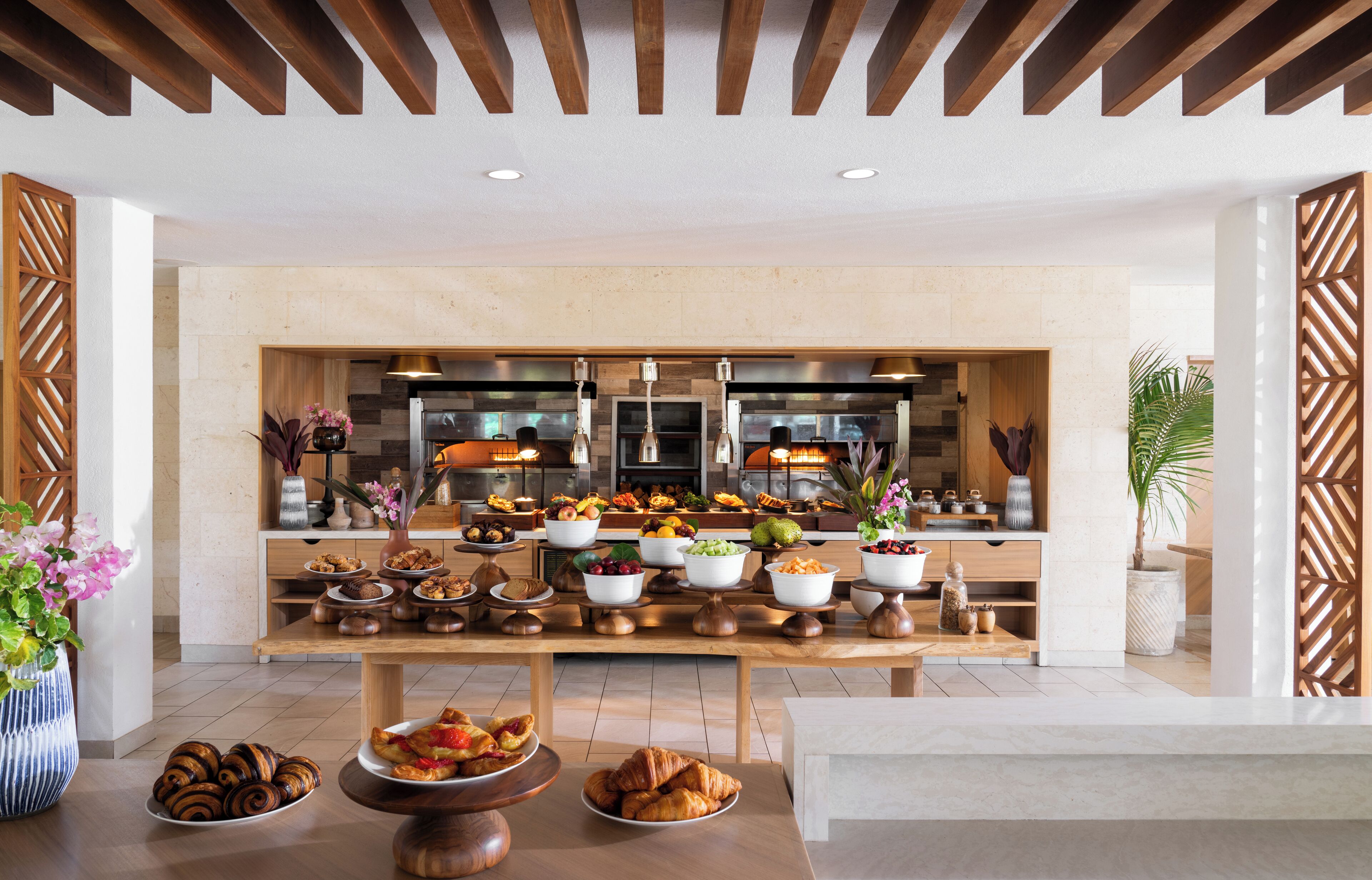 Disposição de buffet com diversos alimentos e estrutura de teto em madeira.