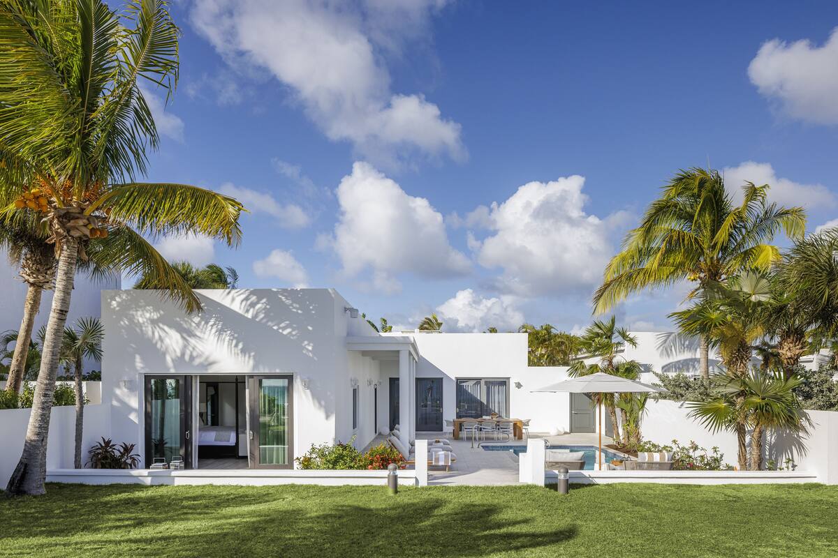 Uma casa moderna com piscina, cercada por palmeiras e um gramado bem cuidado.