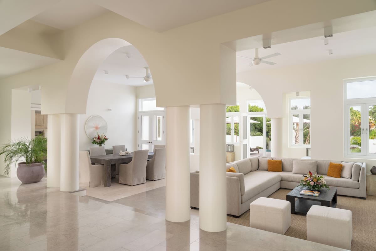 Uma sala de estar ampla com um sofá seccional grande, uma mesa de centro e uma área de jantar com mesa e cadeiras.