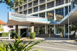 Um hotel moderno com uma placa grande com a inscrição "PACIFIC", uma entrada coberta e uma escadaria que leva ao edifício principal.