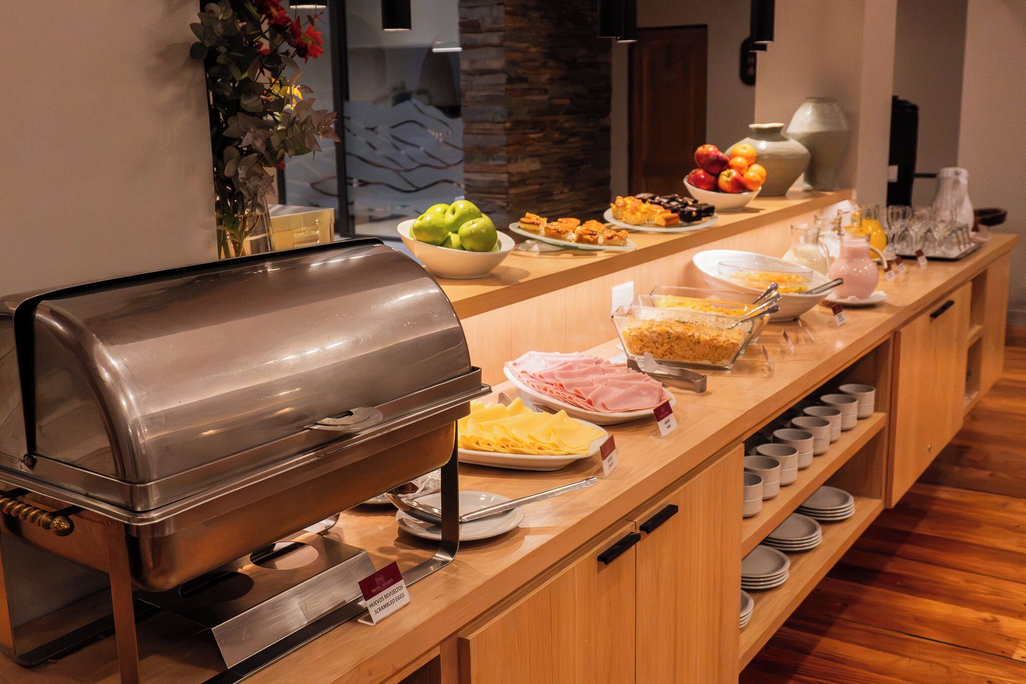 Buffet com diversas opções de comida, incluindo frutas, queijos e carnes.