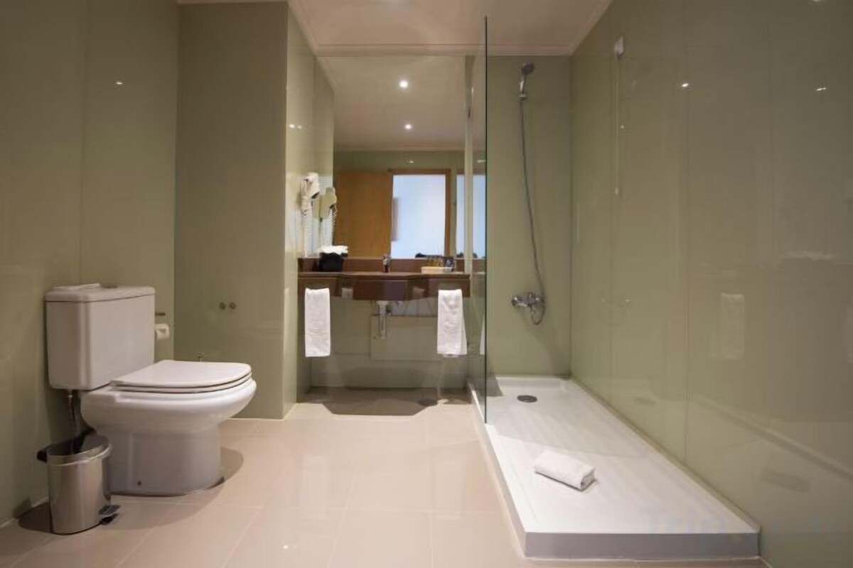 Casa de banho moderna com sanita, chuveiro e zona de duche com divisória de vidro.