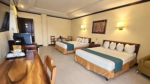 Quarto de hotel com duas camas, uma secretária com máquina de café, televisão e um quadro na parede.