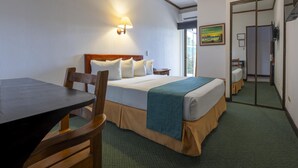 A hotel room with a bed, a desk, and a chair.