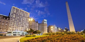 Um hotel com vários andares, um obelisco imponente e uma área de jardim bem iluminada.