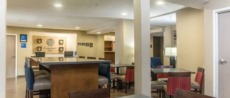 Um hall de hotel com recepção, área de estar e placa da Comfort Inn.