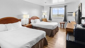Quarto de hotel com duas camas, uma escrivaninha, uma televisão e uma janela com vista.