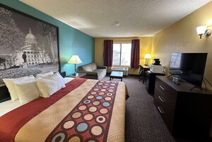 Quarto de hotel com uma cama grande, uma escrivaninha, uma televisão e um quadro de um edifício.