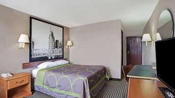 Quarto de hotel com cama, escrivaninha, televisão e porta.