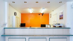 Uma área de recepção com balcão, relógio e mural de avisos.