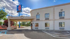 Um motel com um letreiro grande, área de estacionamento coberta e um edifício com várias janelas.