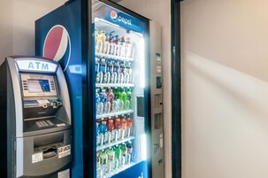 Um caixa eletrônico e uma geladeira Pepsi com diversas bebidas.