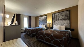 Quarto de hotel com duas camas, uma mesa e uma janela grande.