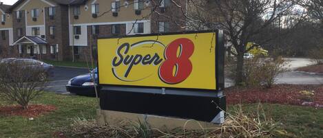 Placa do hotel Super 8, com um edifício de tijolos ao fundo.