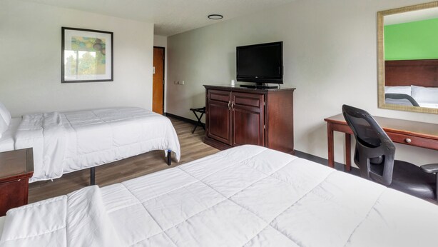 Quarto de hotel com duas camas, uma escrivaninha, uma cadeira, televisão e um quadro na parede.