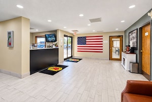 Um saguão de hotel com balcão de recepção, uma bandeira americana e um espaço para café.