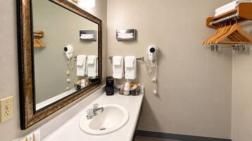Casa de banho de hotel com um espelho grande, uma pia, porta-toalhas e um secador de cabelo.