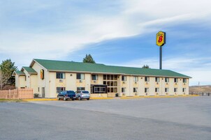 Um motel com telhado verde, várias janelas e uma placa em um mastro.