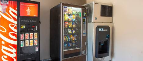 Uma máquina de Coca-Cola, uma máquina de vendas de lanches e um dispensador de gelo.