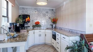 Cozinha moderna com armários brancos, bancadas de granito e painel de parede decorativo.