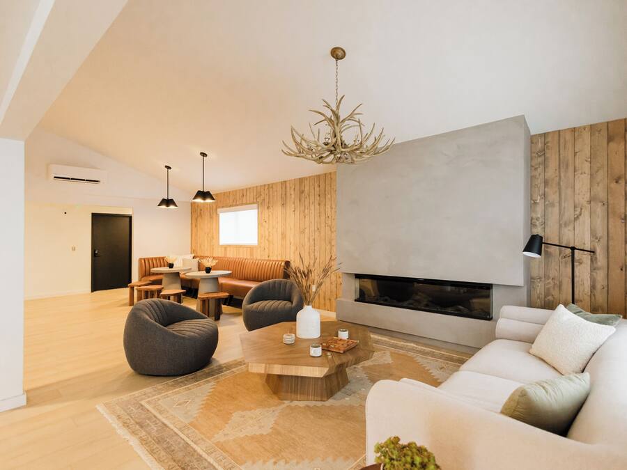 Uma sala de estar moderna com lareira, paredes de madeira e uma grande janela.